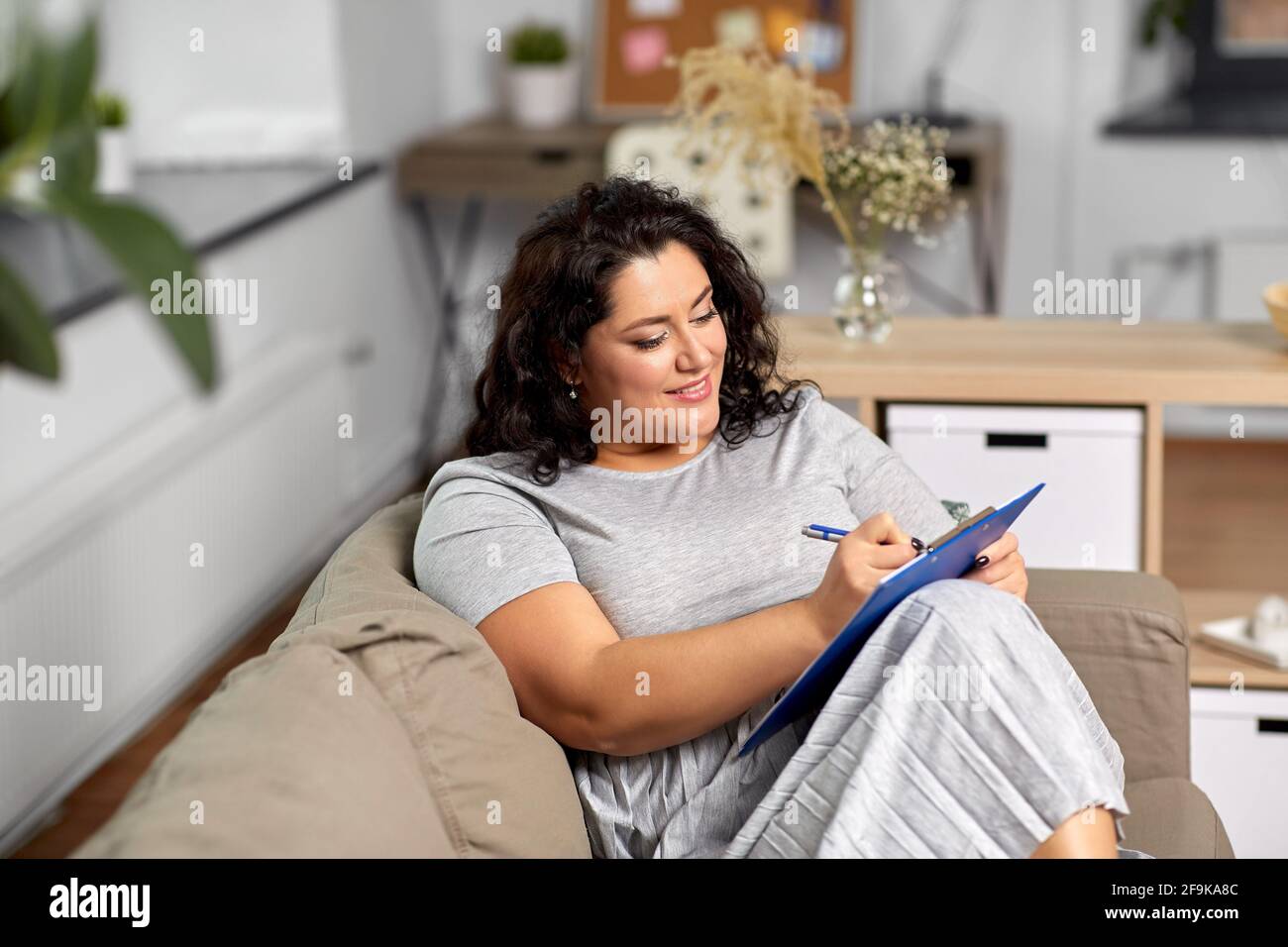 young woman with clipboard taking notes at home Stock Photo - Alamy
