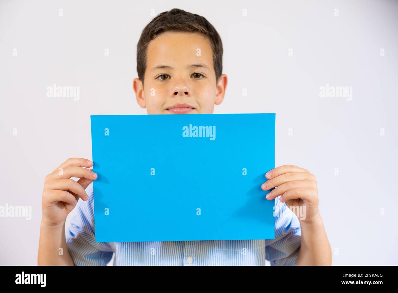 Cute boy holding blue blank paper isolated over white background Stock ...
