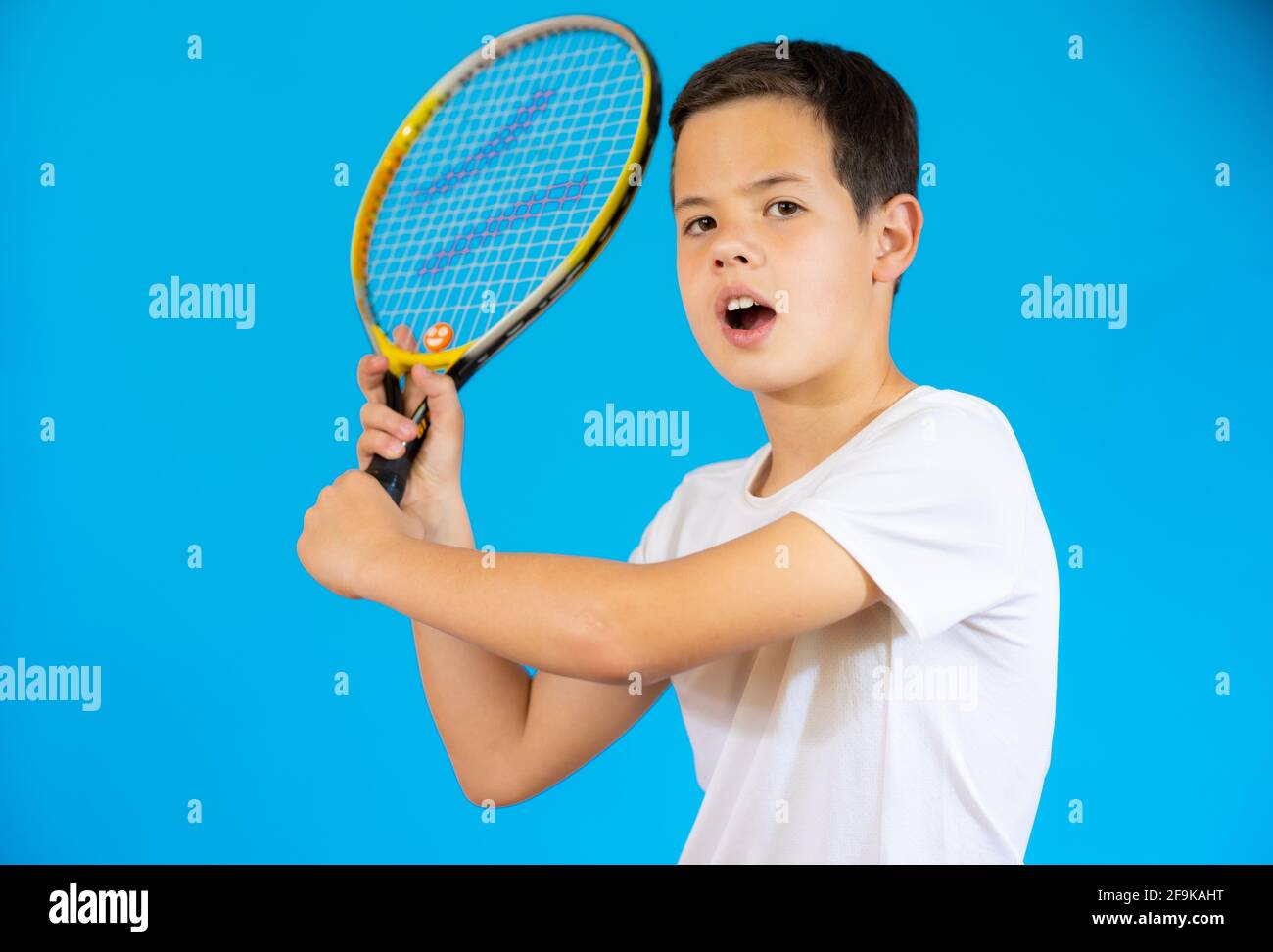 Young boy with tennis racket isolated over blue background Stock Photo ...