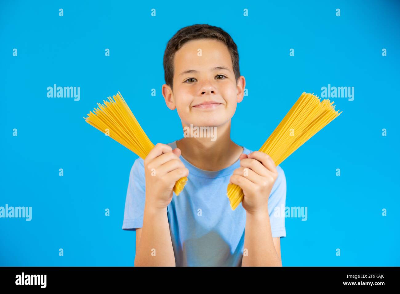 Cute smiling boy holding traditional Italian spaghetti in his hands ...