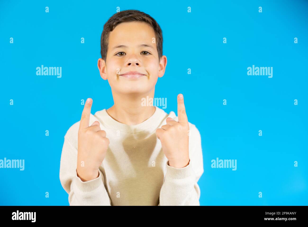 Cheerful smiling boy pointing up over blue background Stock Photo - Alamy