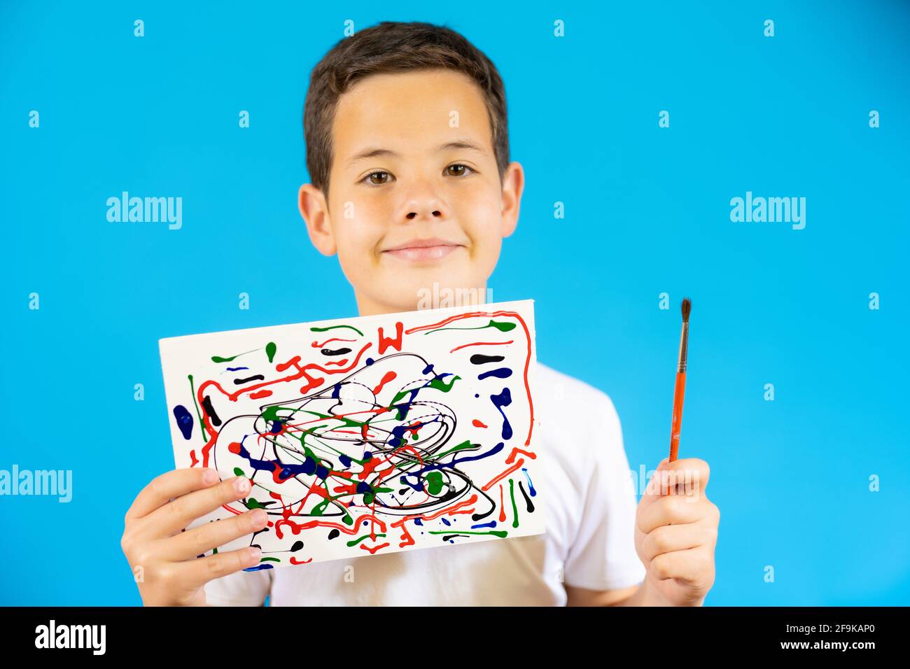 Happy cheerful child drawing with brush using a lot of painting tools ...
