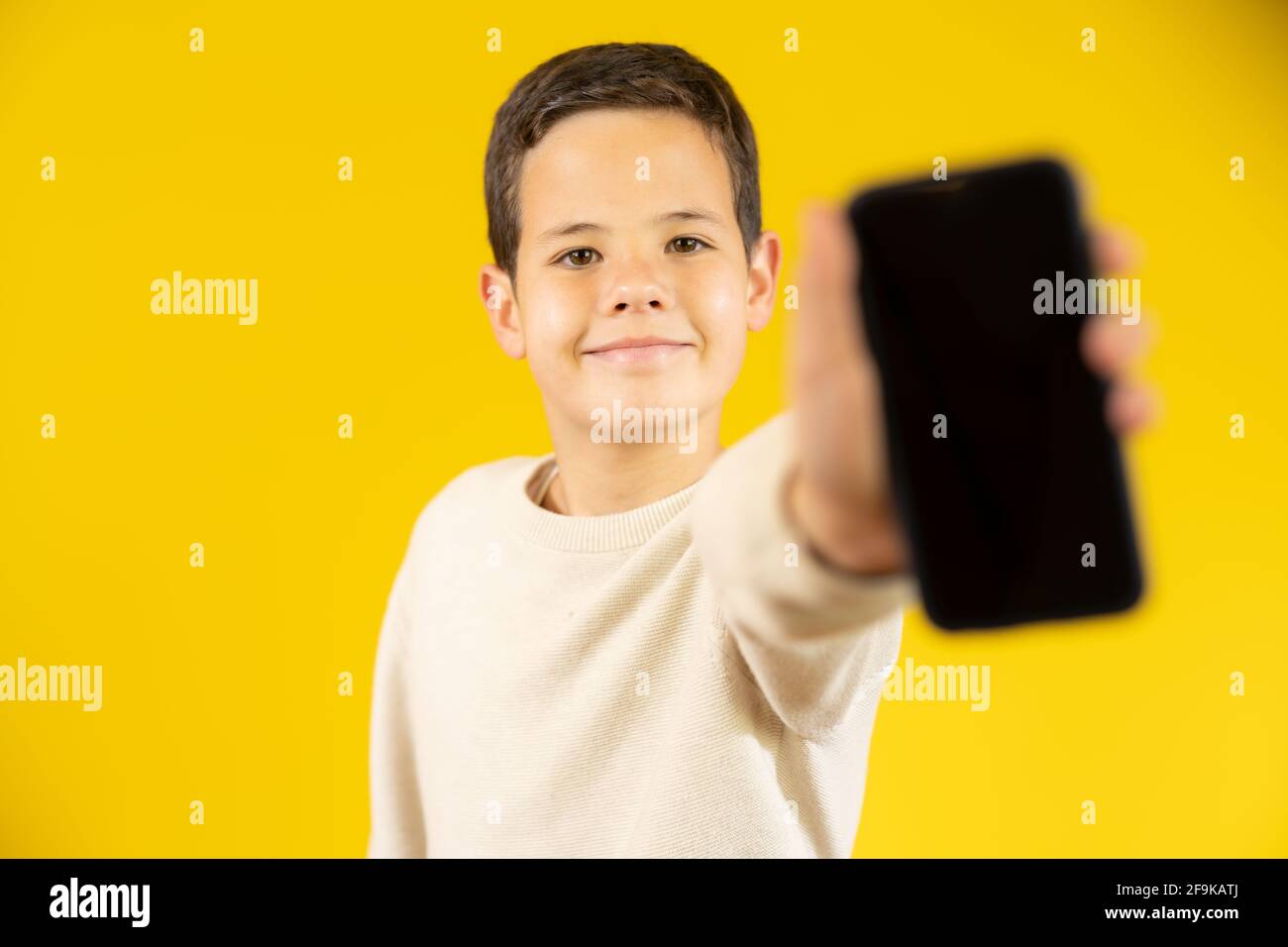 Cute boy showing mobile phone isolated over yellow background Stock ...