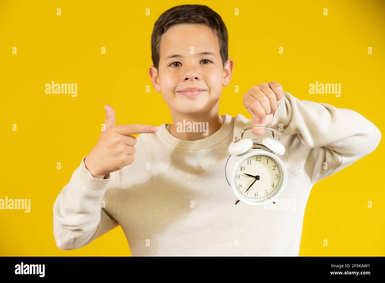 Cute smiling boy pointing with finger an alarm clock isolated over ...