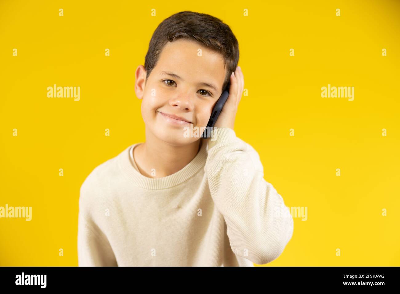Cute boy talking on mobile phone isolated over yellow background Stock ...