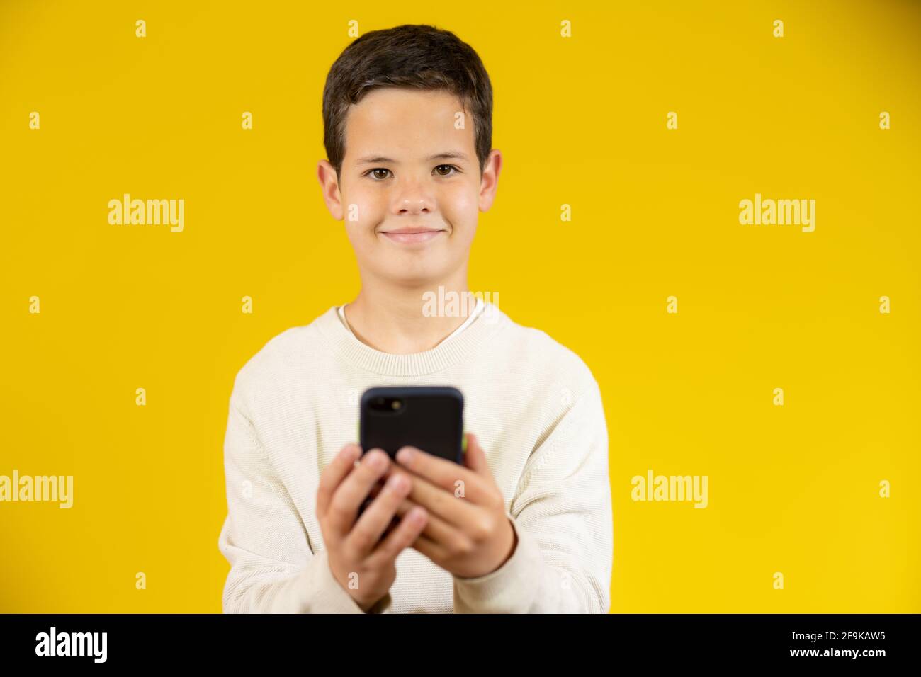 Cute boy using mobile phone isolated over yellow background Stock Photo ...