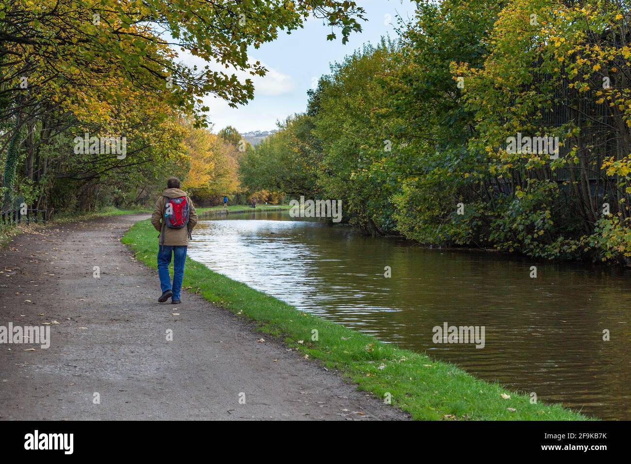 A man walks along the towpath of the Leeds Liverpool Canal at Saltaire ...