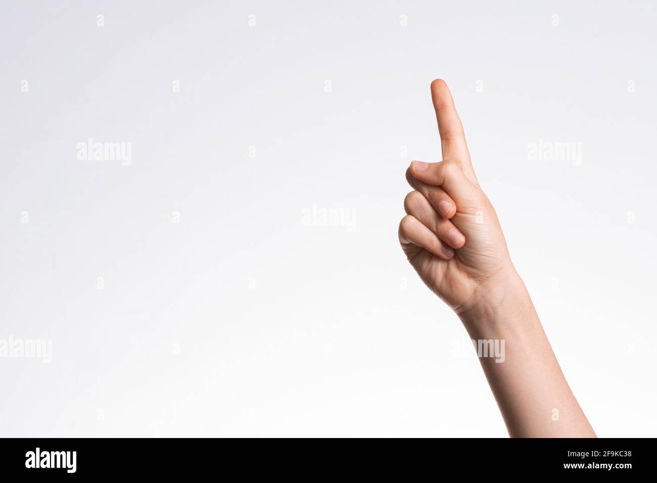 Hand pointing, shows number one gesture with index finger on white wall ...
