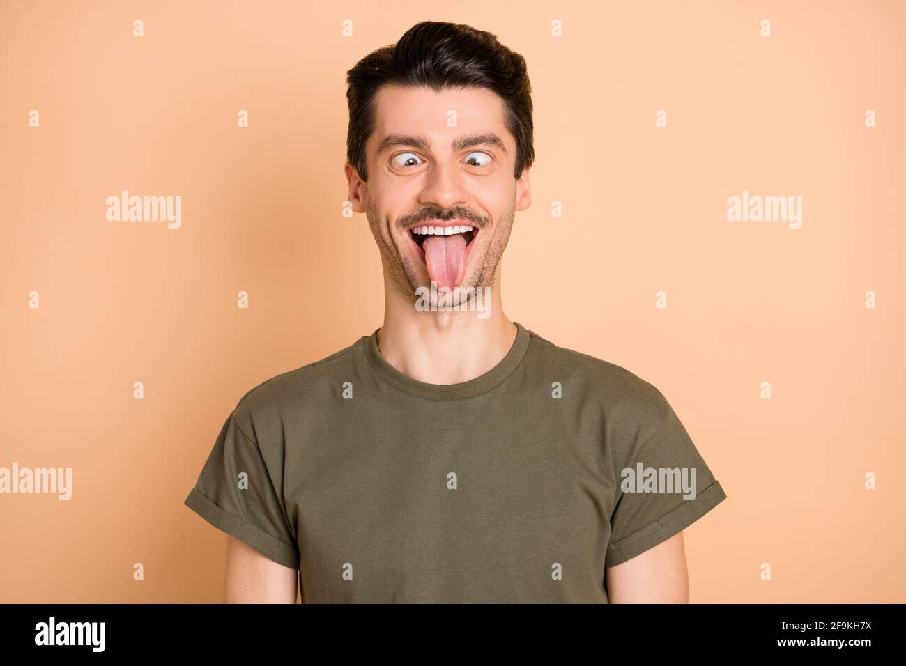Photo of foolish guy crossing eyes stick out tongue wear green t-shirt ...