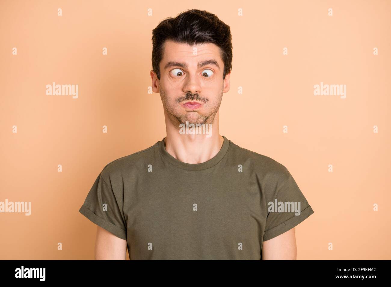 Photo of funky guy crossing eyes puffed cheeks have fun wear green t ...