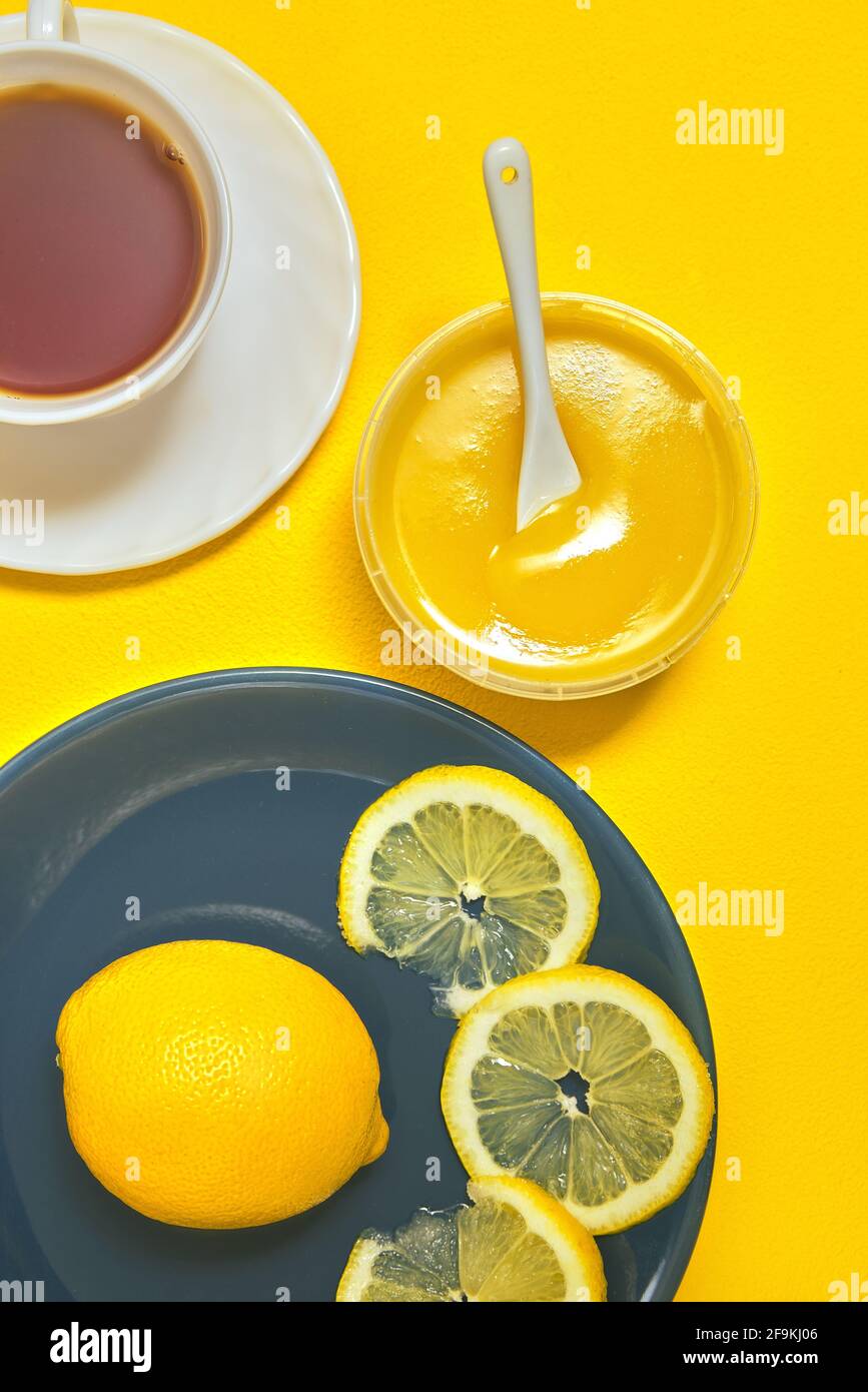 fresh lemon sliced in slice on blue plate. there is tea and jar of ...