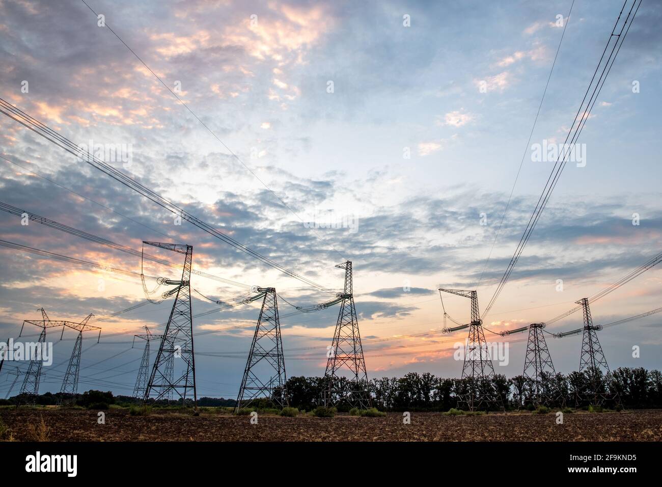 Electrical pylons and high voltage power lines at sunset background ...
