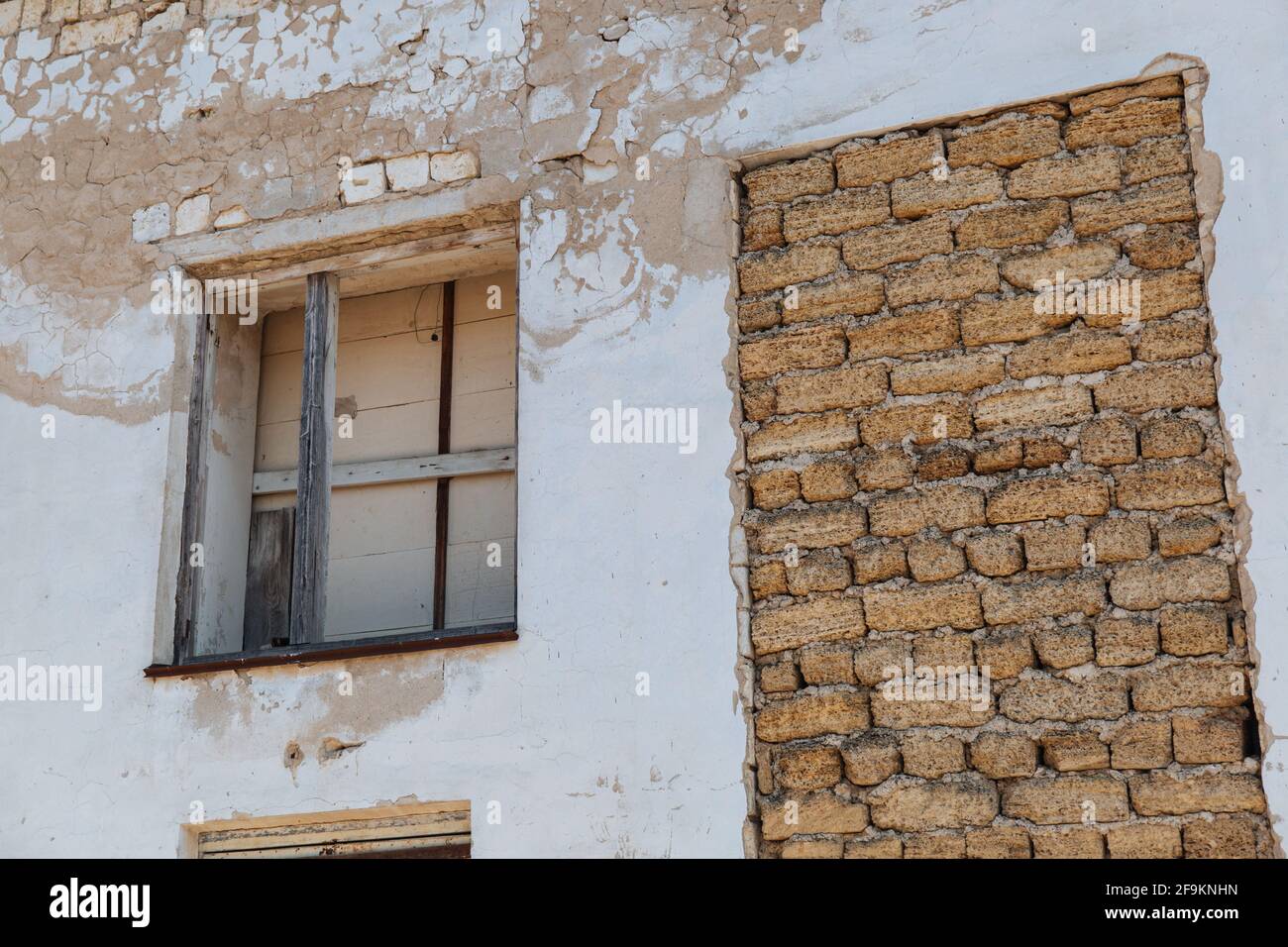 An old wall of an abandoned crumbling house with a boarded-up window ...