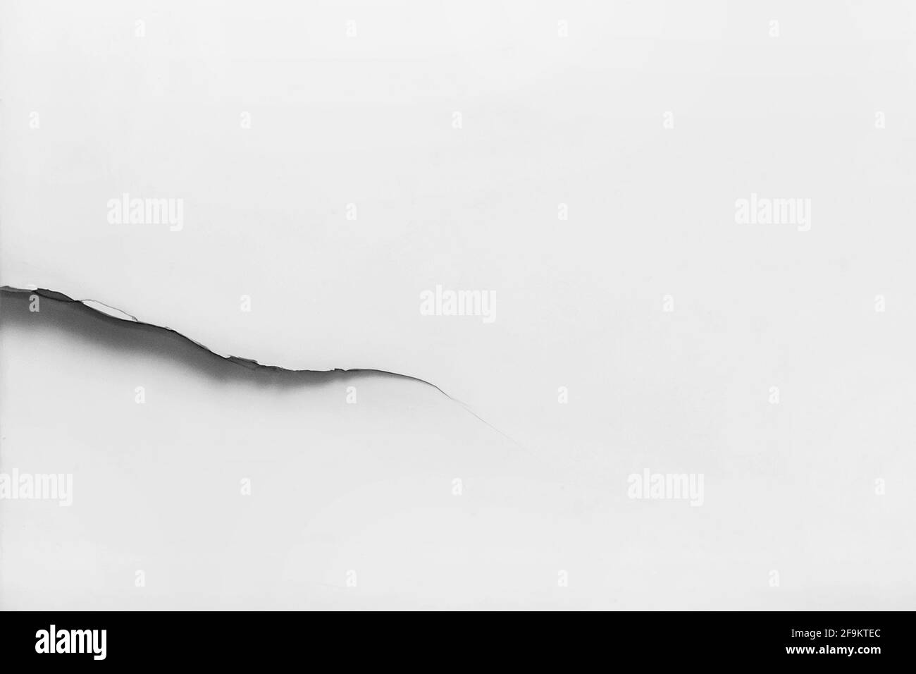Large crack on a white damaged wall, broken light background, copy ...