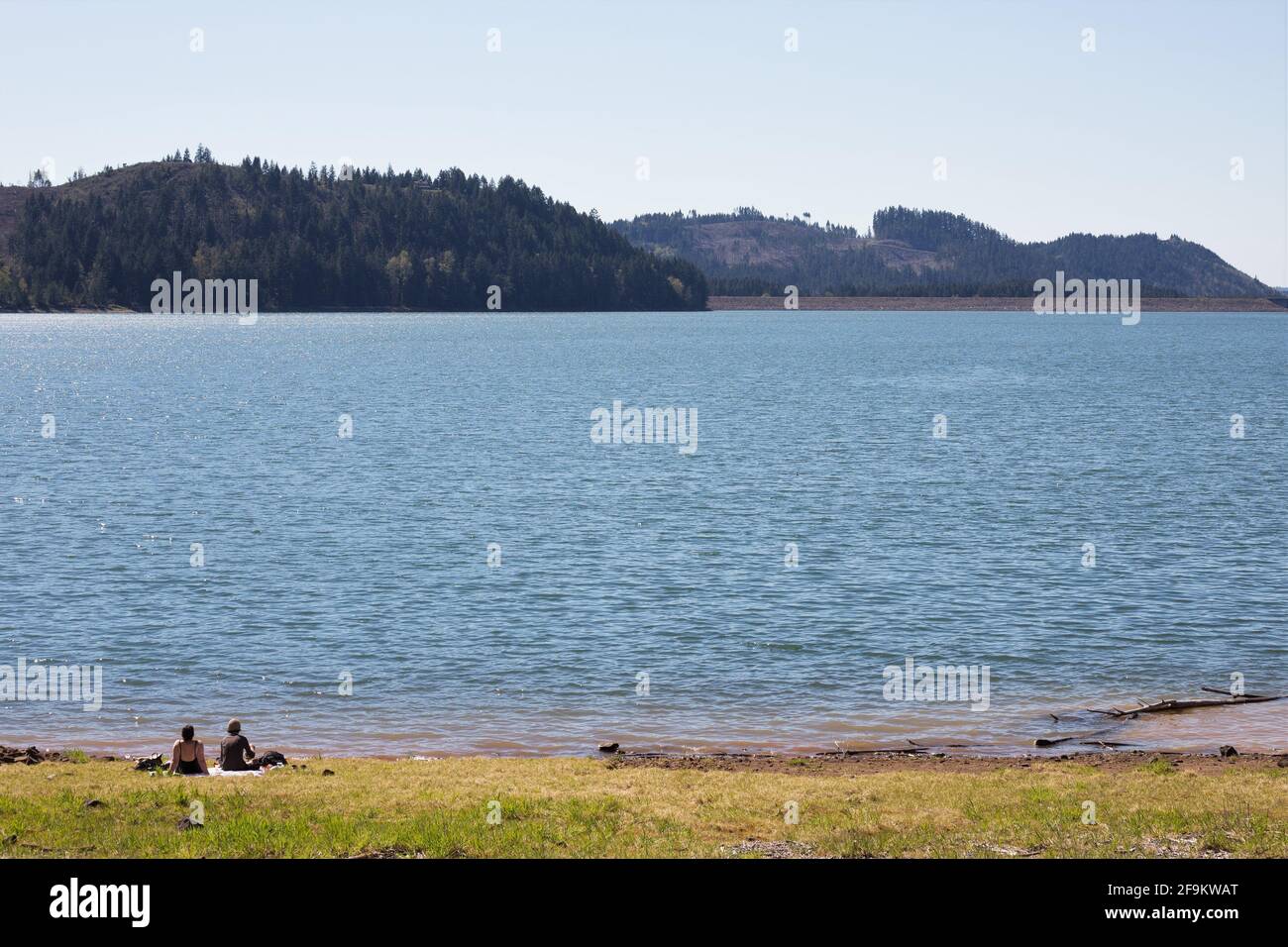 Two people sitting on the bank of Dorena Lake in Cottage Grove, Oregon ...