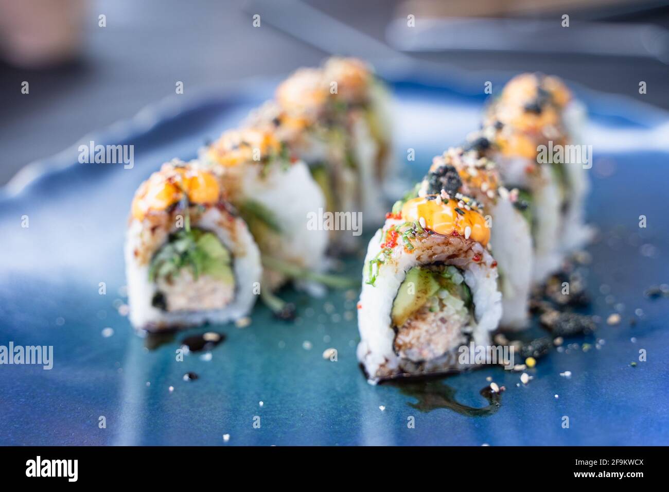 Crab maki sushi roll with Thai sauce and tobiko on blue plate ...