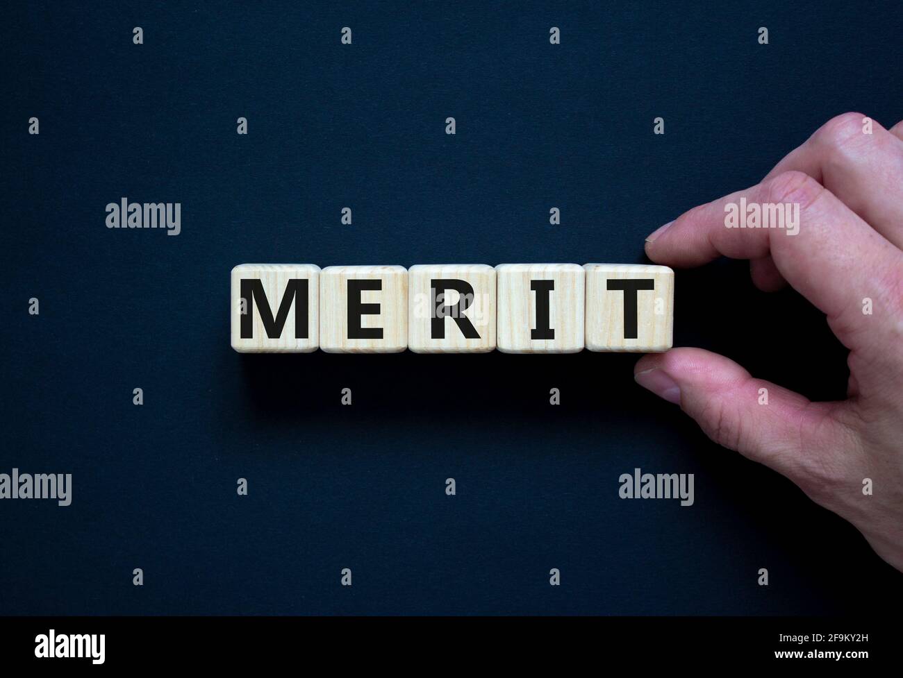 Merit symbol. Wooden cubes with the word 'merit'. Businessman hand ...