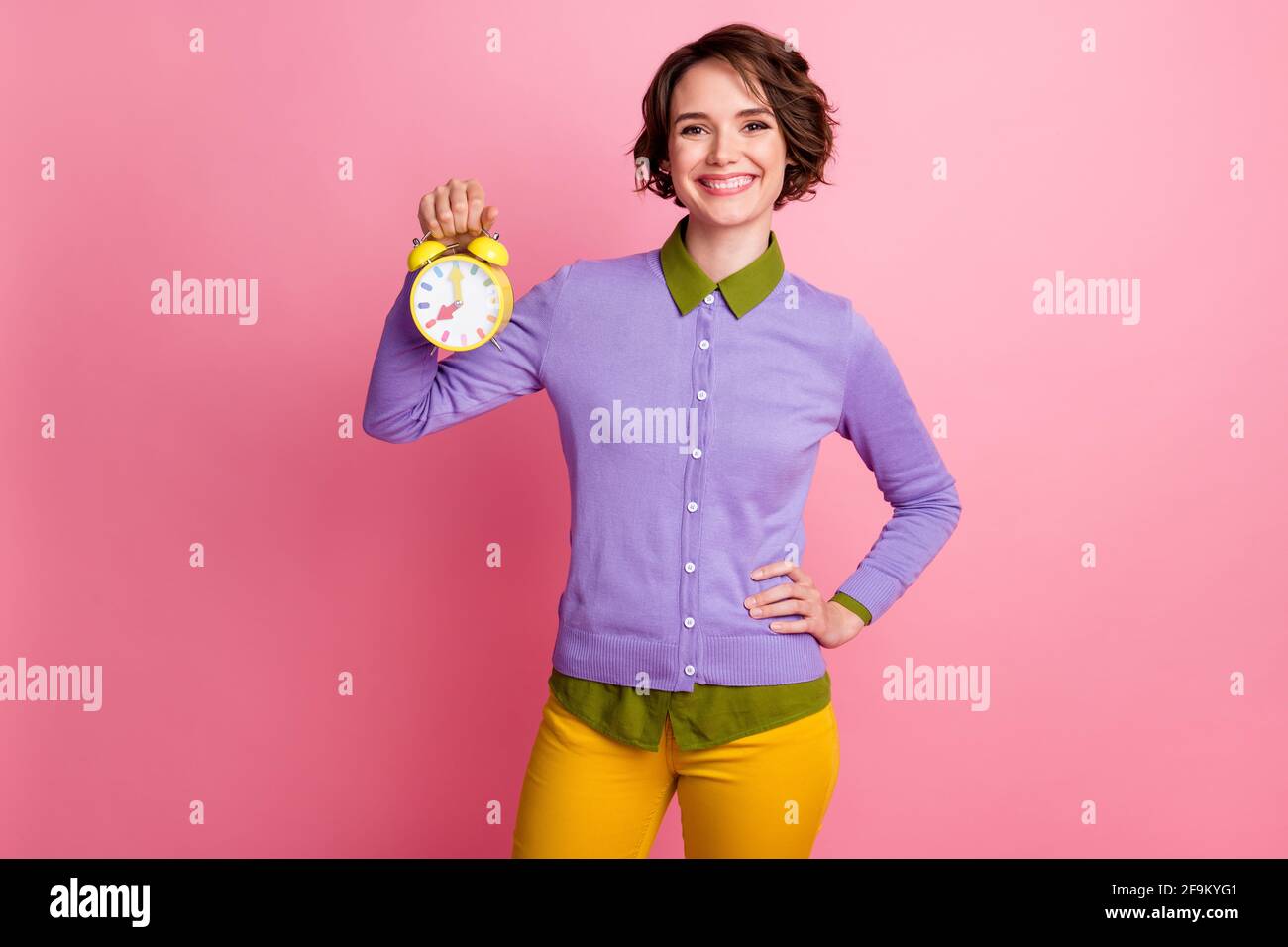 Photo of positive girl hold clock wear outfit isolated over pink color ...