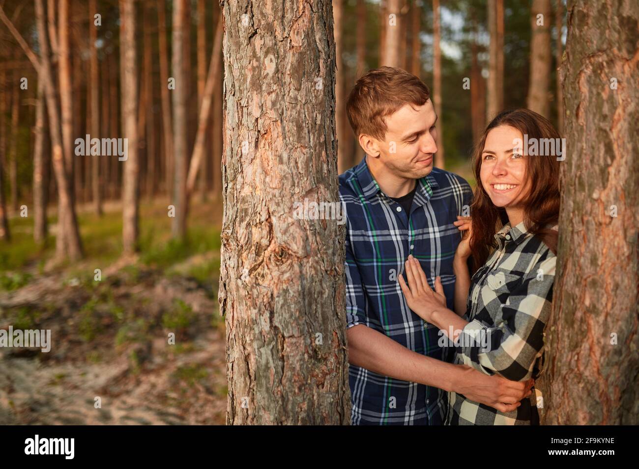 young couple smiling at each other during a romantic date in the forest ...