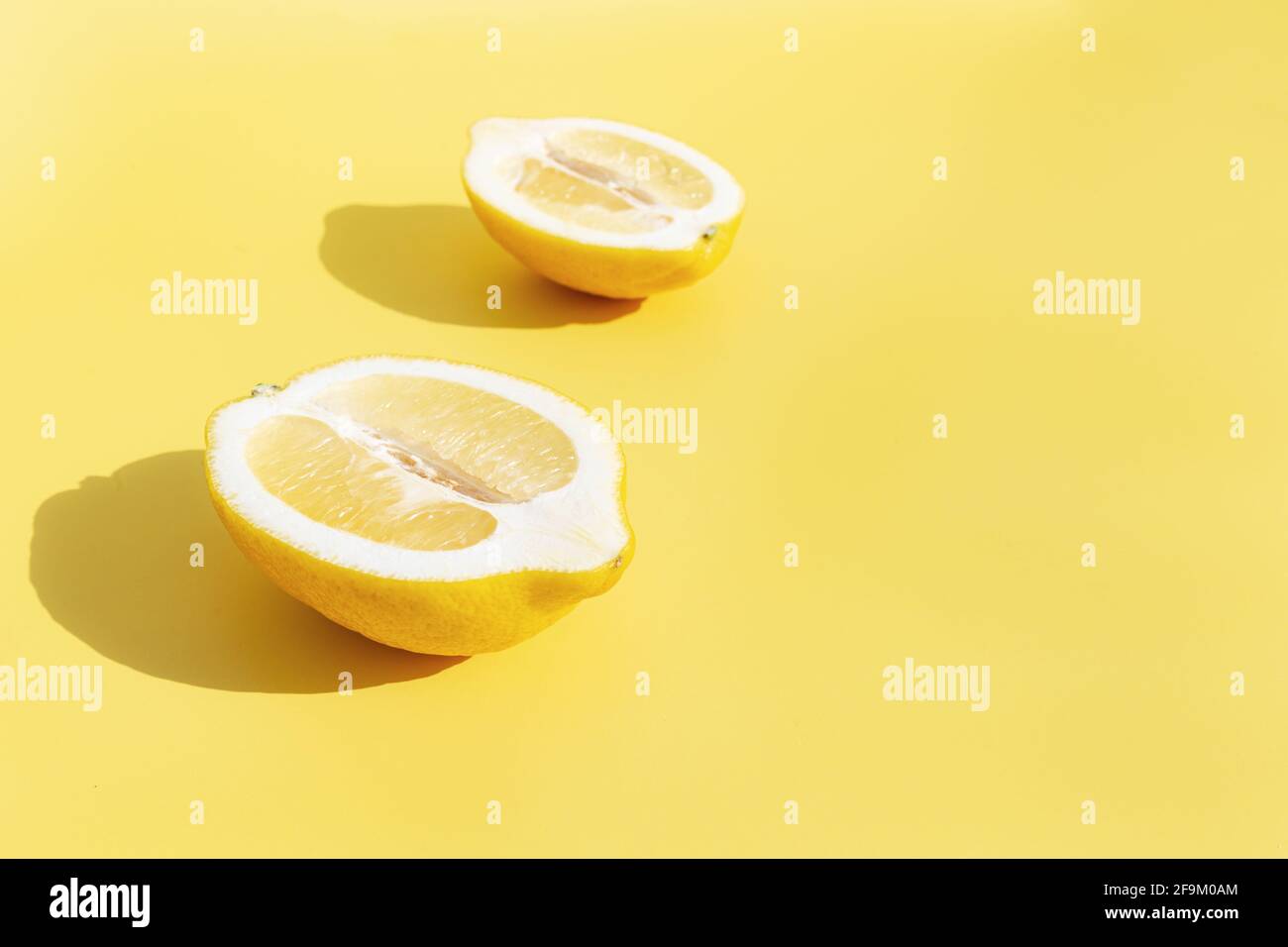 Two halved cuts of lemon with shadow on yellow background. Healthy ...