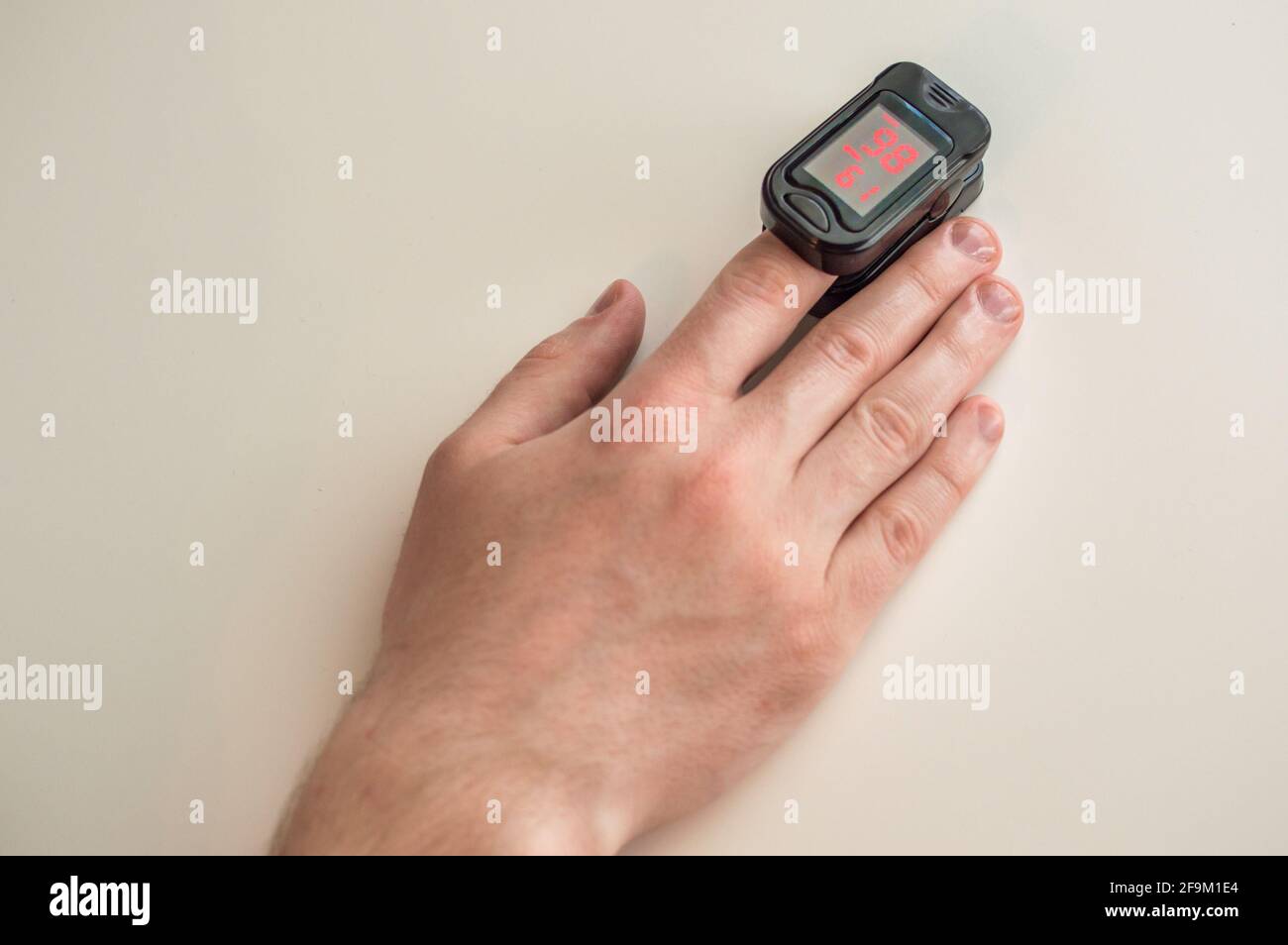 pulse oximeter is placed on the index finger of a man's hand to measure ...