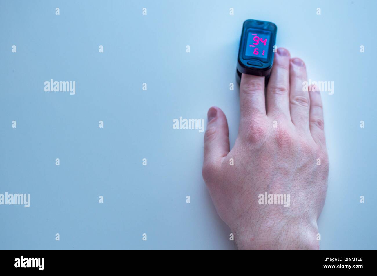 pulse oximeter is placed on the index finger of a man's hand to measure ...
