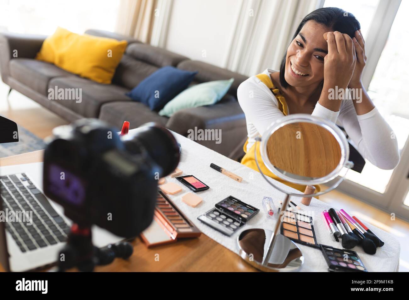 Happy mixed race transgender woman making vlog using laptop and camera ...
