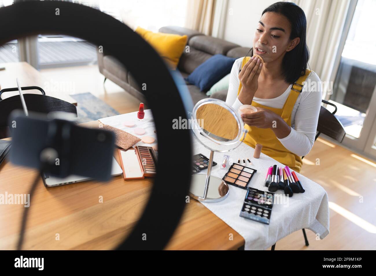 Mixed race transgender woman making vlog using laptop, smartphone and ...