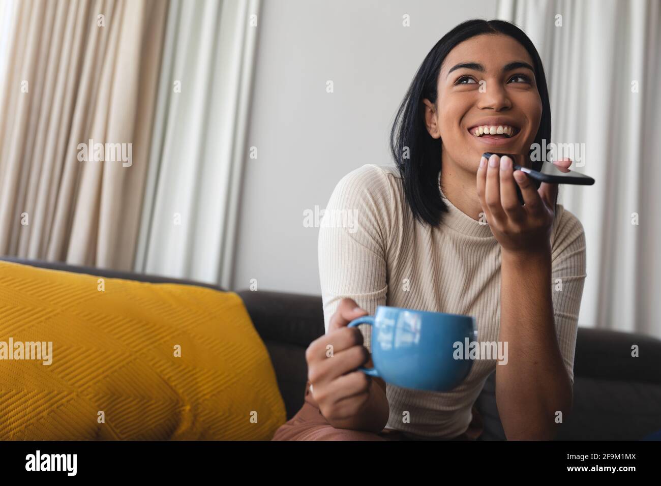 Happy mixed race transgender woman relaxing in living room sitting on ...