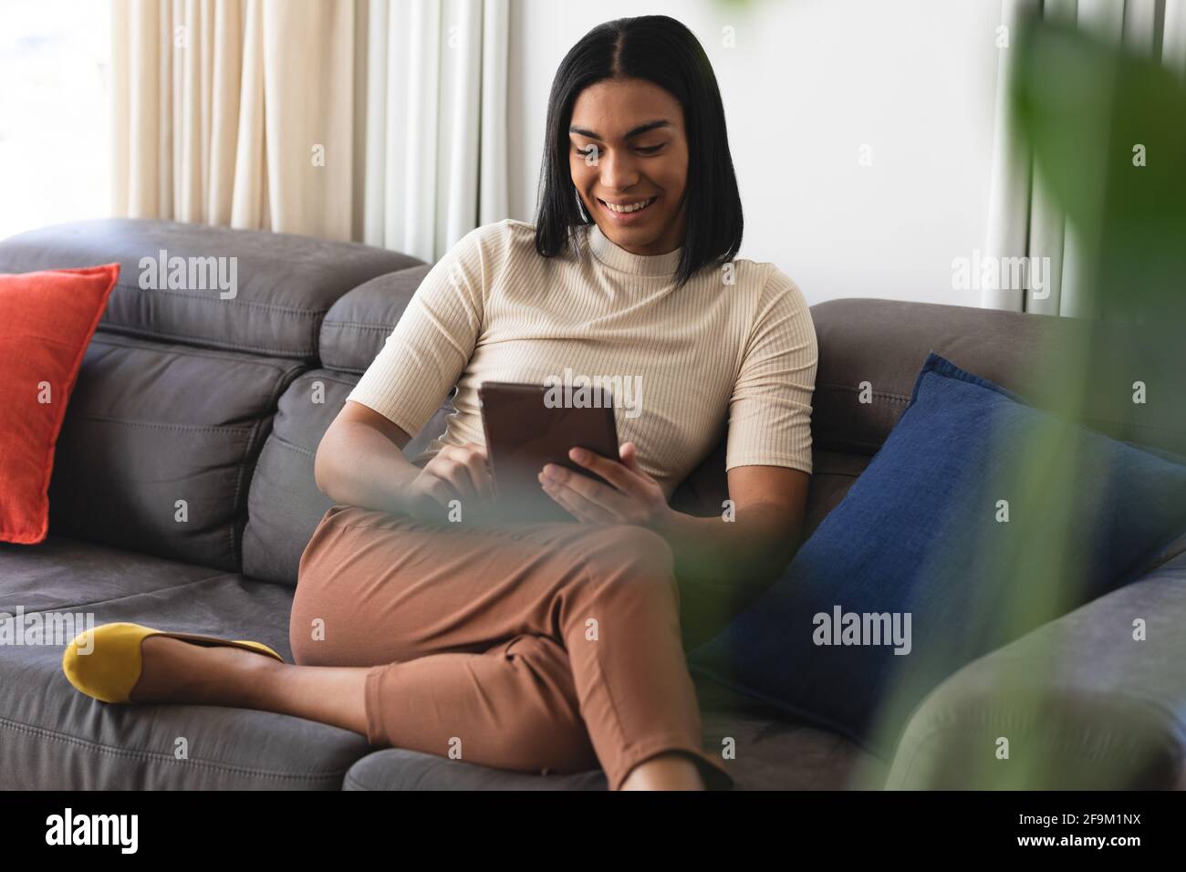 Happy mixed race transgender woman relaxing in living room sitting on ...
