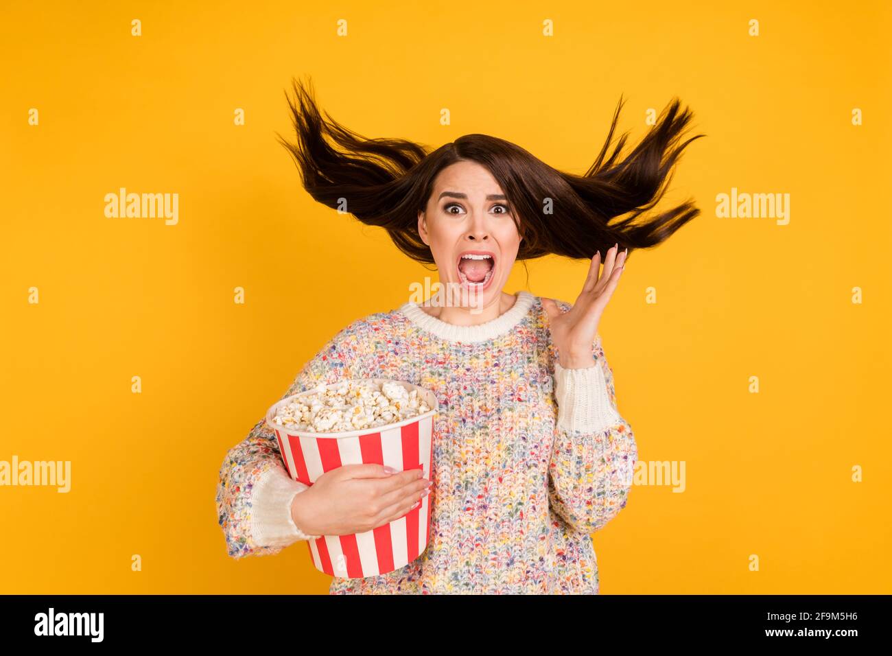 Photo of scared crazy young woman fly hair wind hold pop corn bucket ...