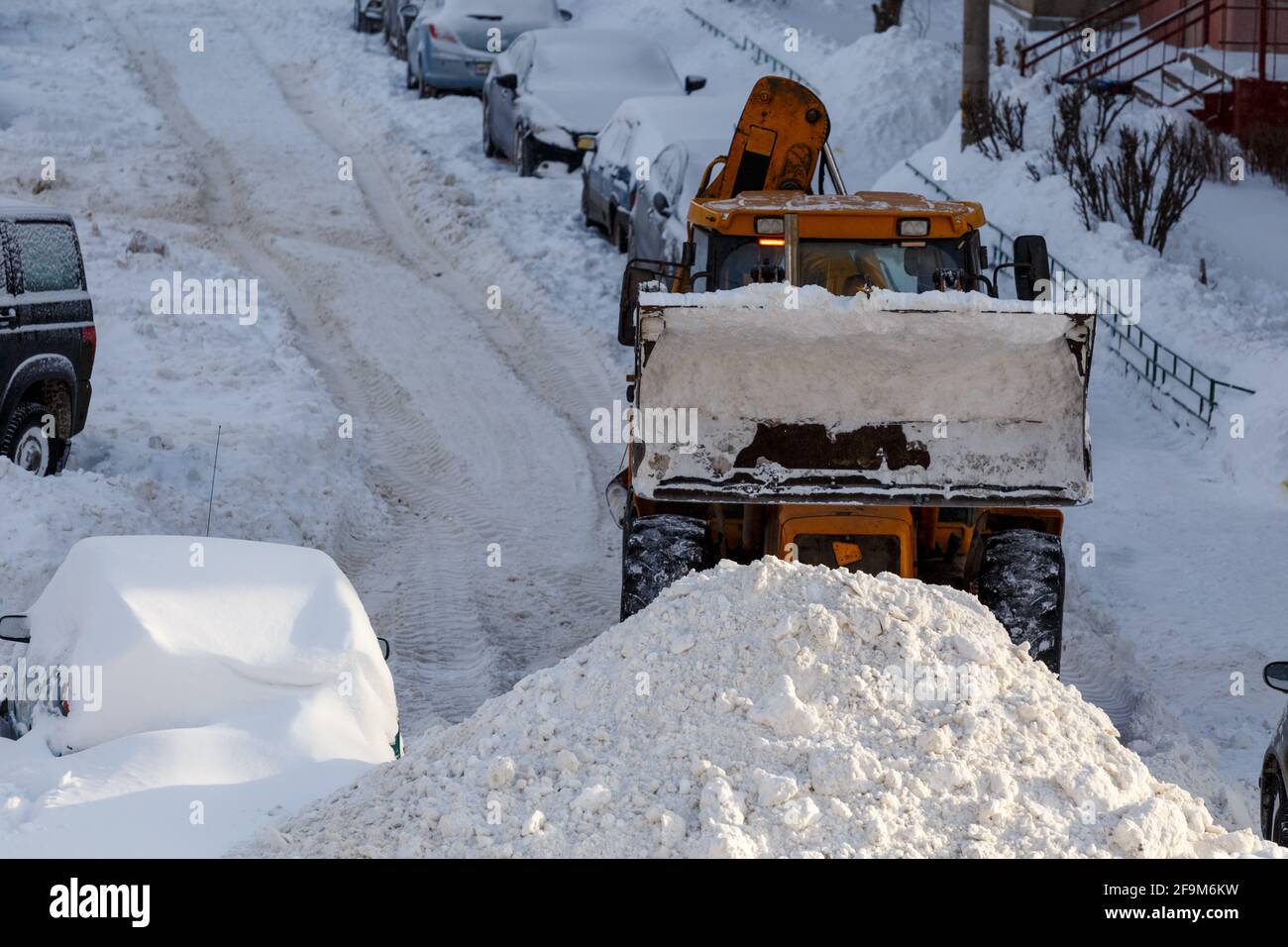 tractor removing snow from parking near residential building at winter ...