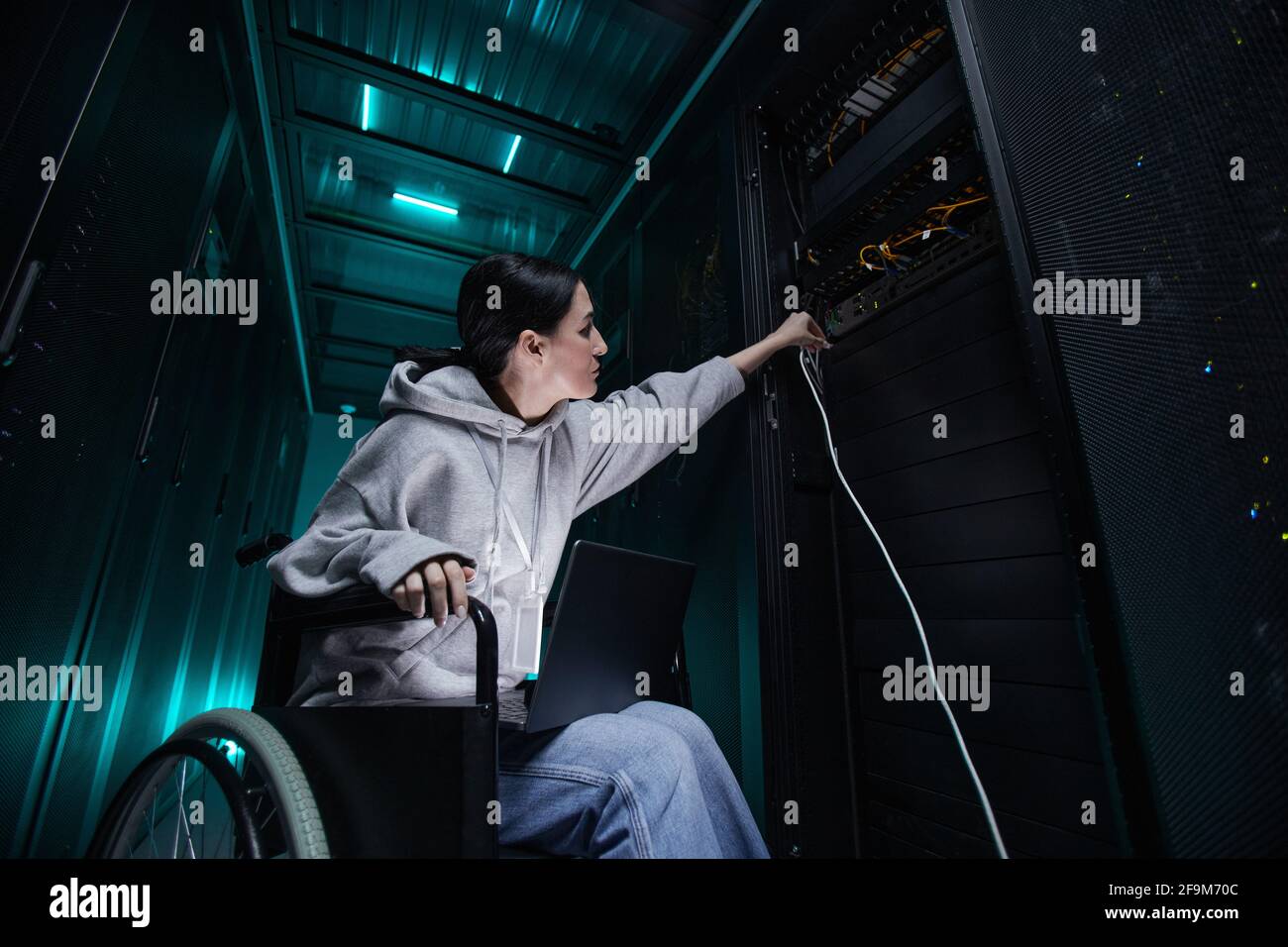 Low angle portrait of disabled woman in wheelchair working with ...