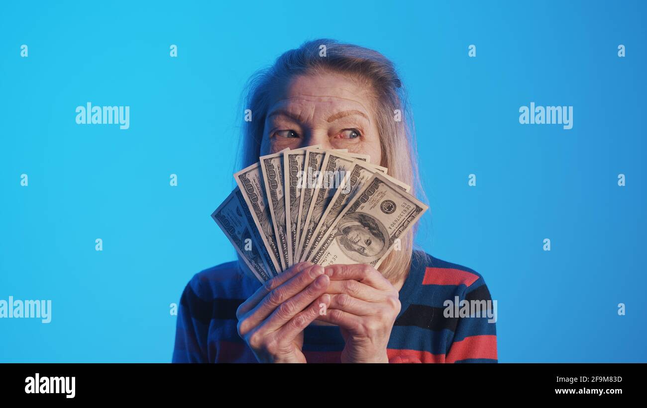 Rich elderly lady holding money fan in front of her face and looking ...