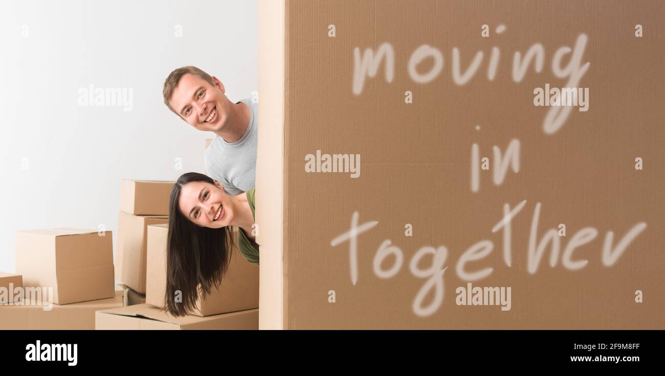 moving in together peekaboo, young happy couple hiding behind box ...