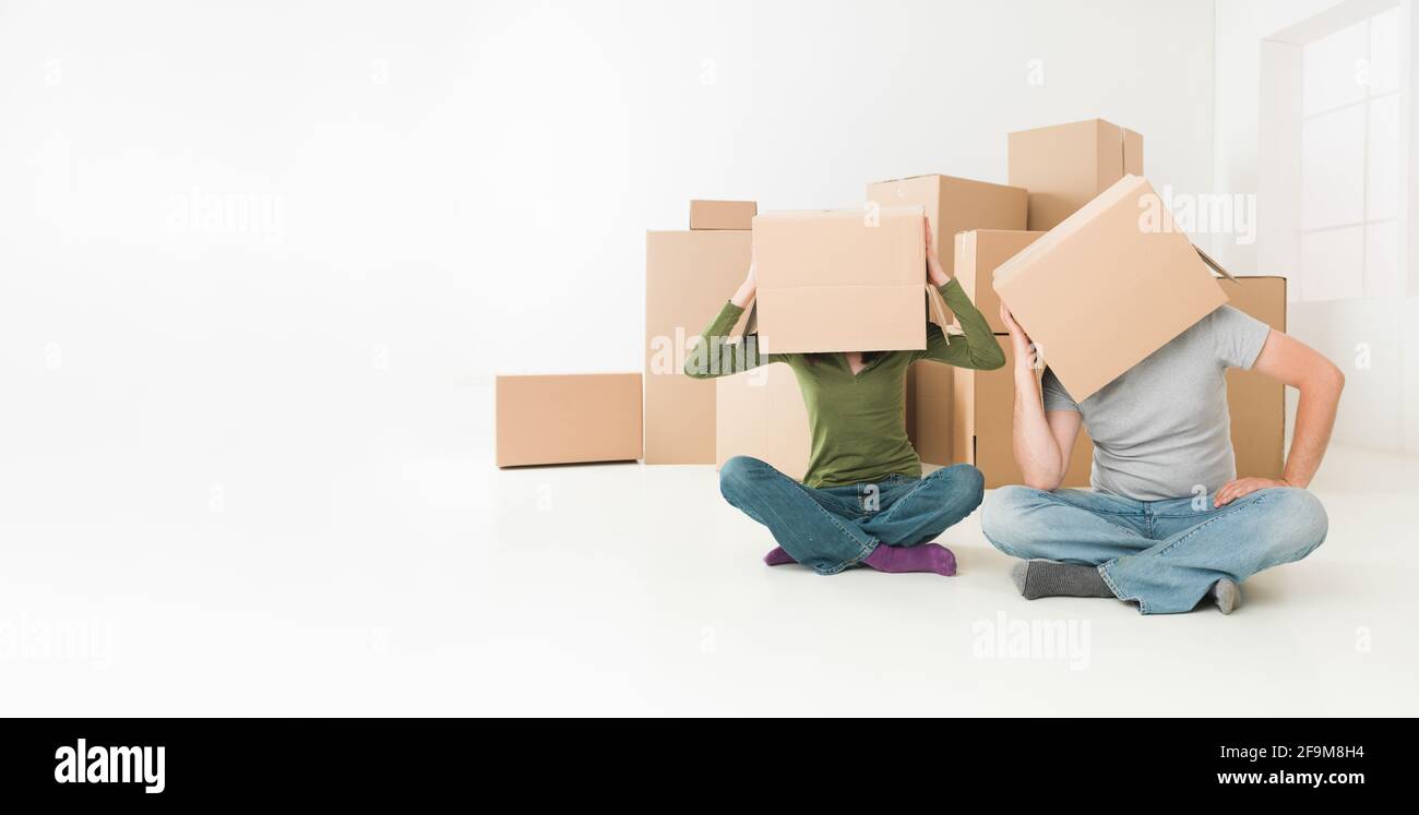 couple with boxes on their heads sitting on floor in their new house ...