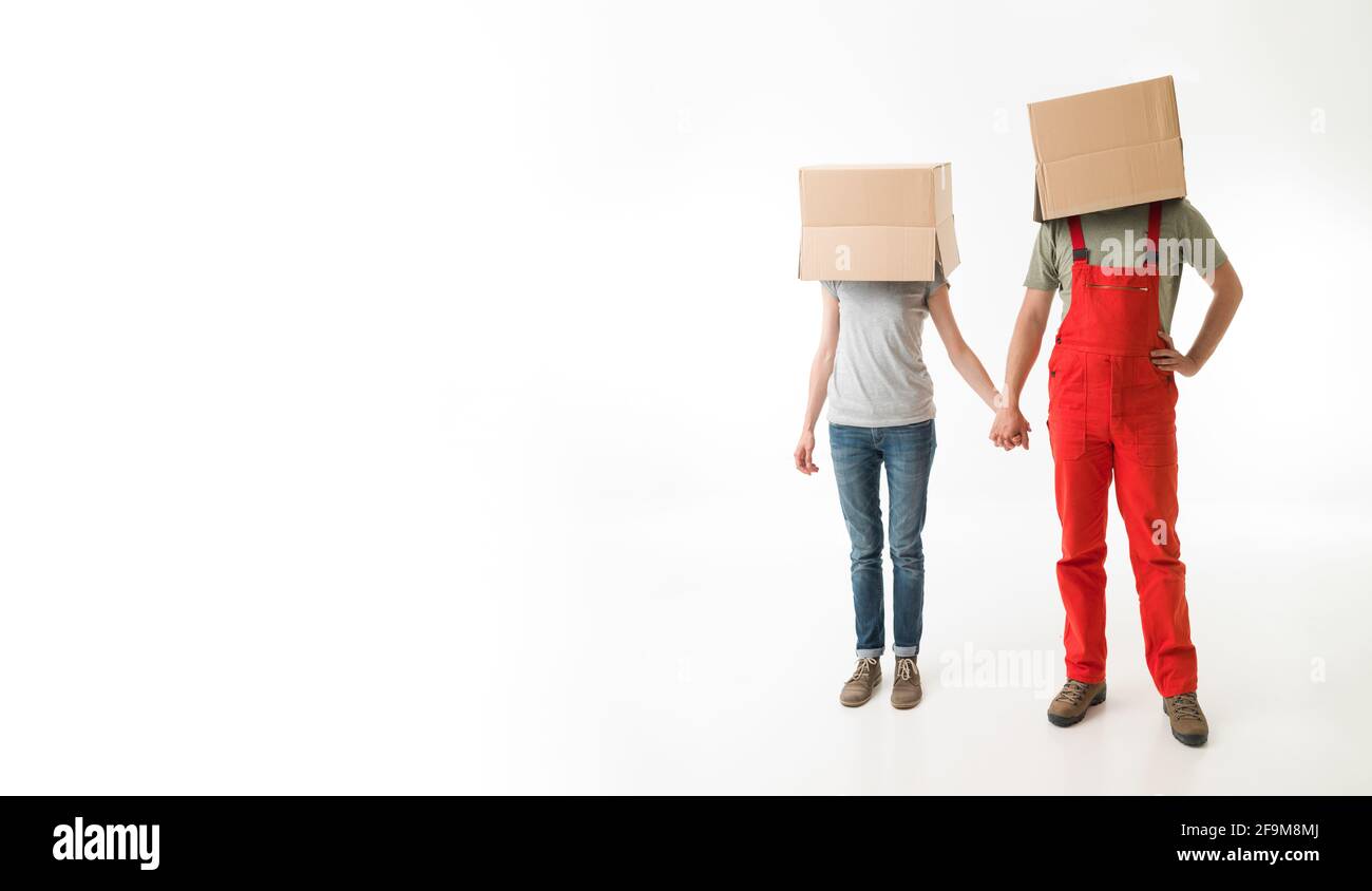 young couple with cardboard boxes on their heads, holding hands, on ...