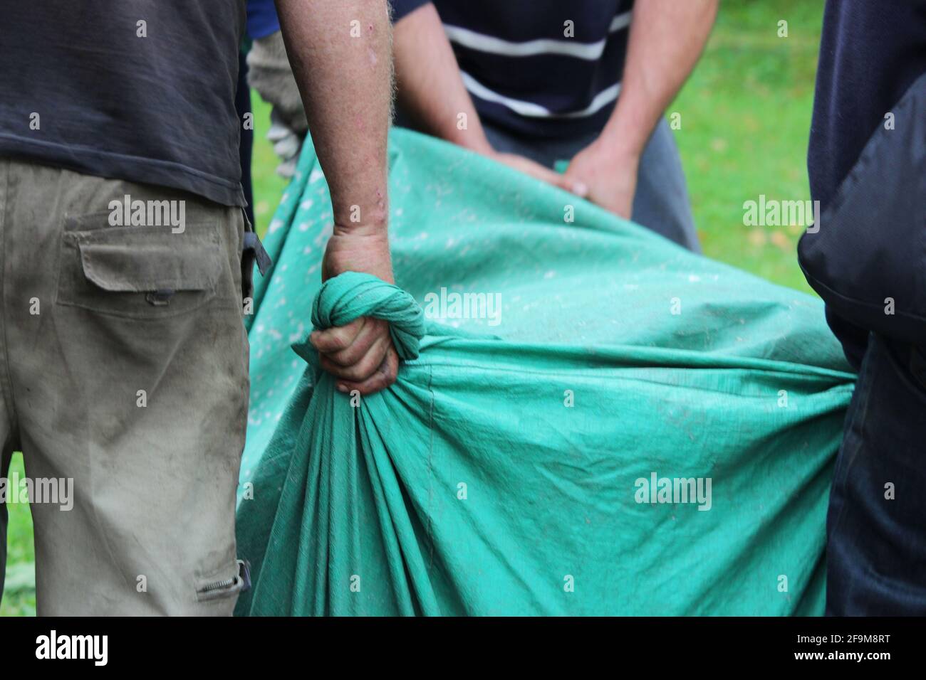 three strong men are dragging a huge green bag with an inflatable ...
