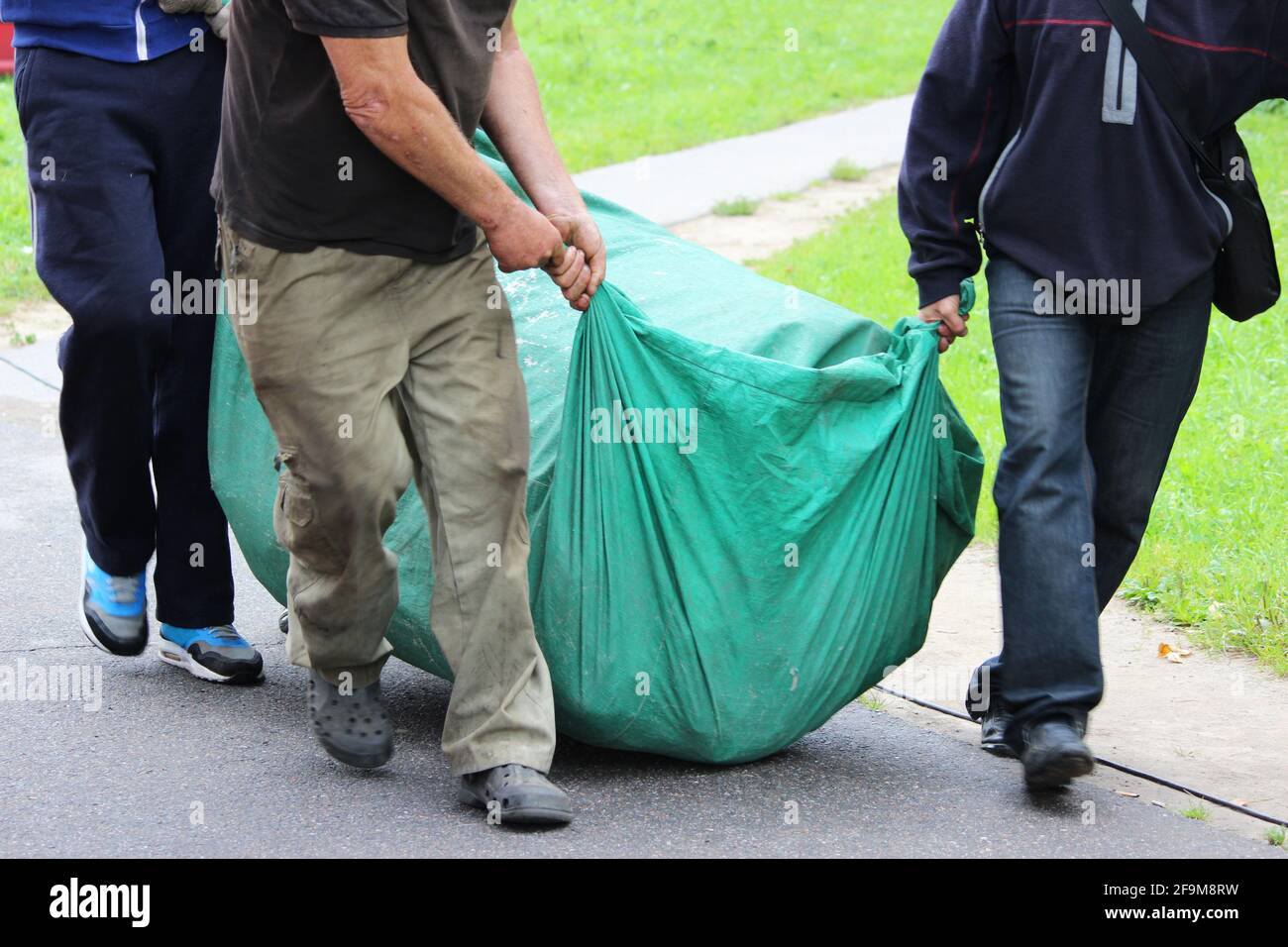 three strong men are dragging a huge green bag with an inflatable ...