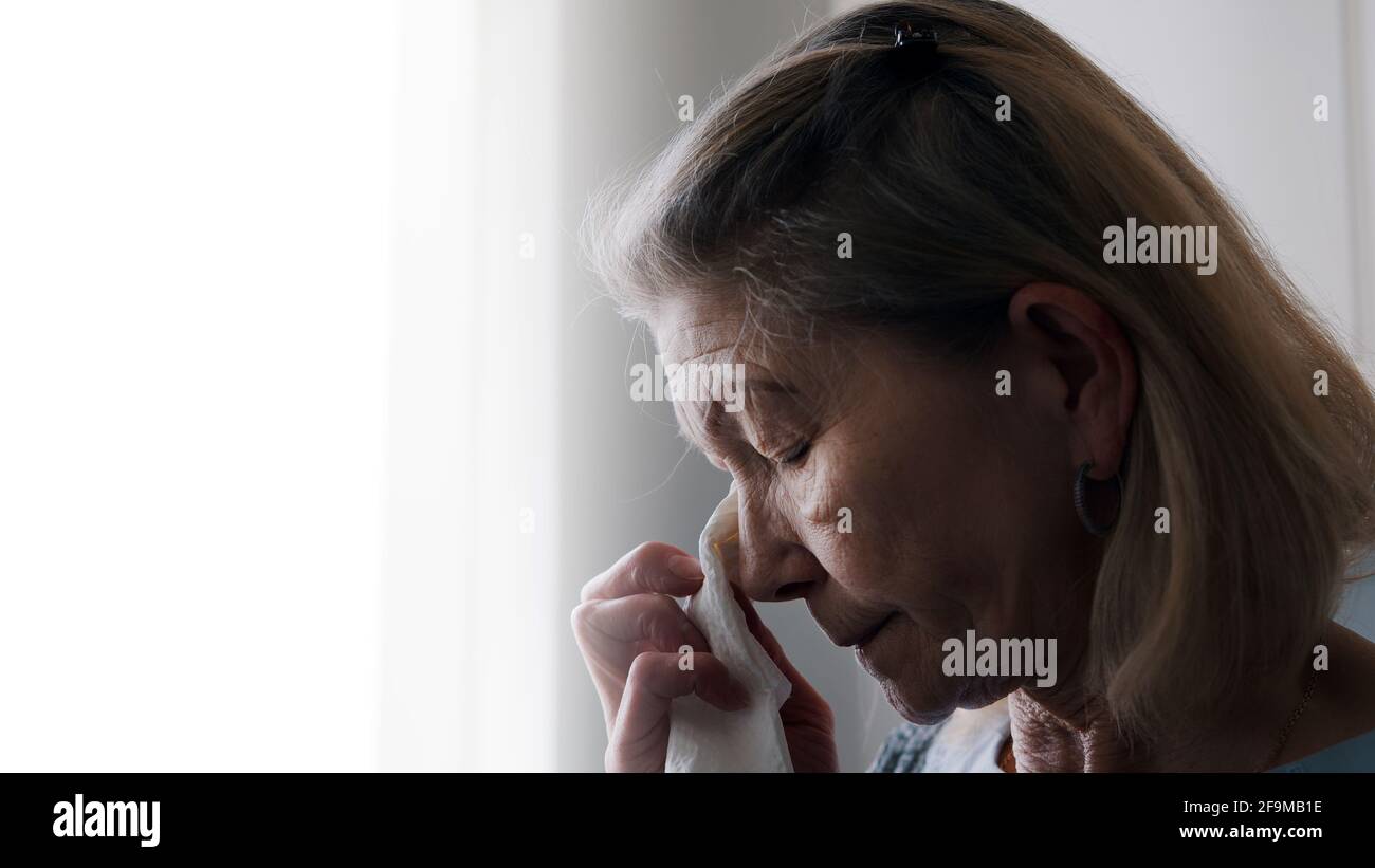 Depressed old lonely woman wiping tears with tissue while looking ...