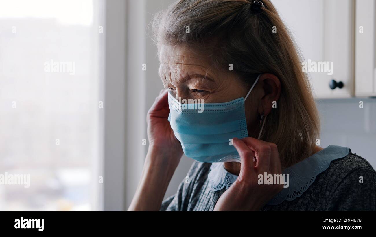 Elderly lonely woman putting on medical mask over her face. High ...