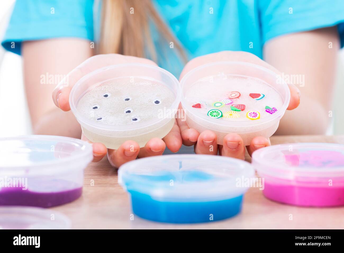The child plays with slimes. The girl shows her slimes in her hands ...