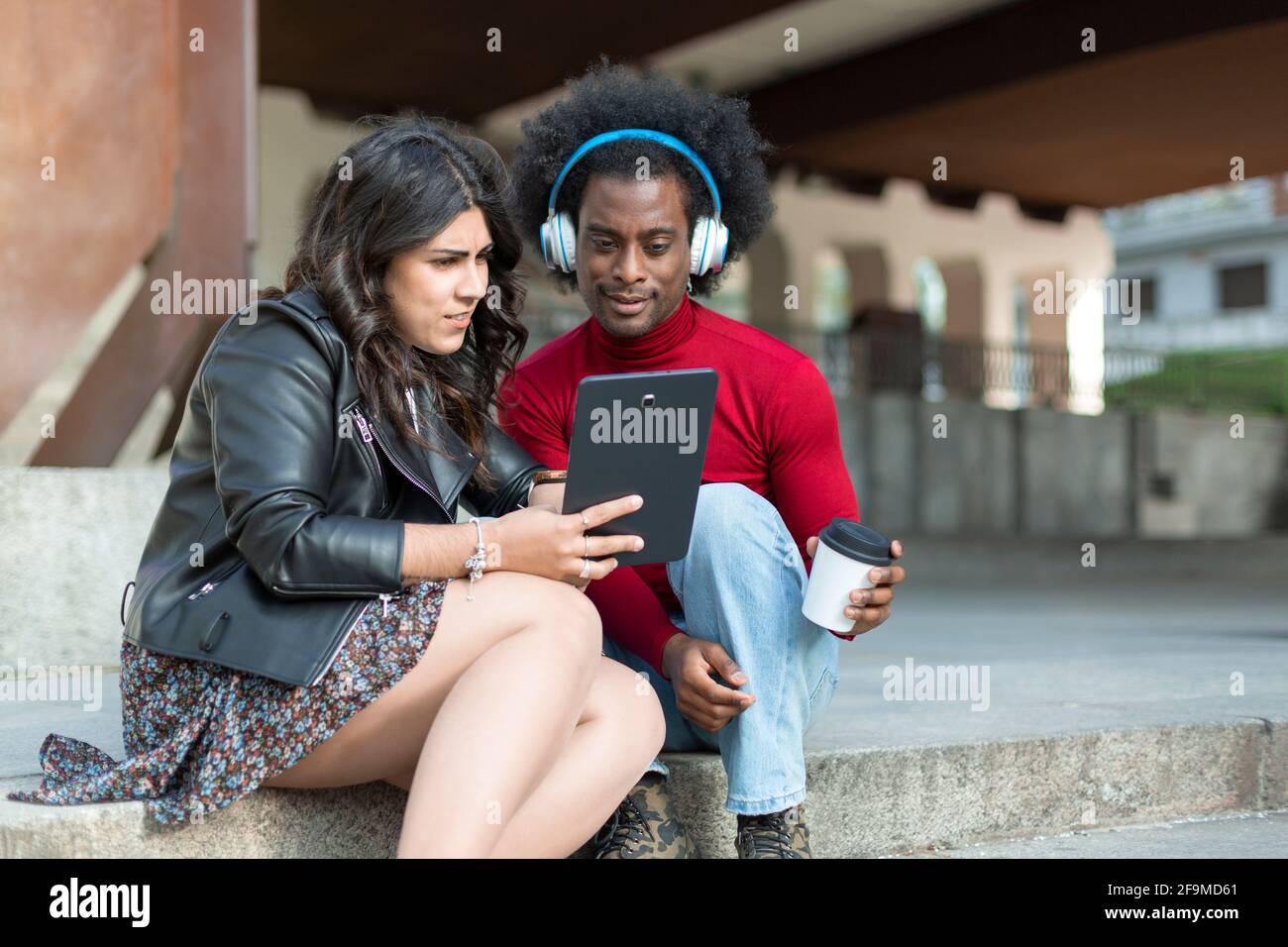 Two good friends sitting outdoors viewing content on a graphics tablet ...
