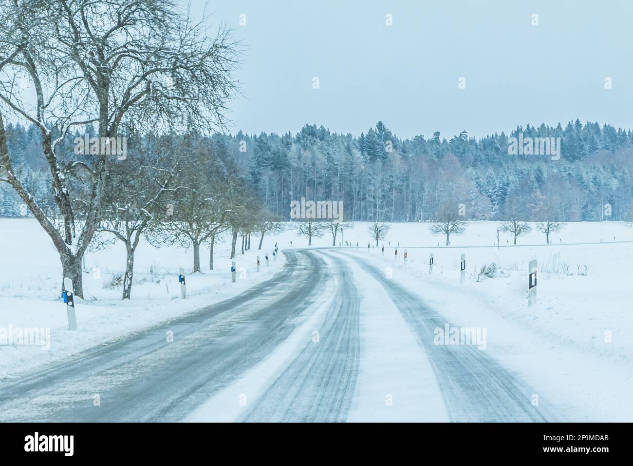 Lonely slippery icy winter road traffic with white snowy track. The ...