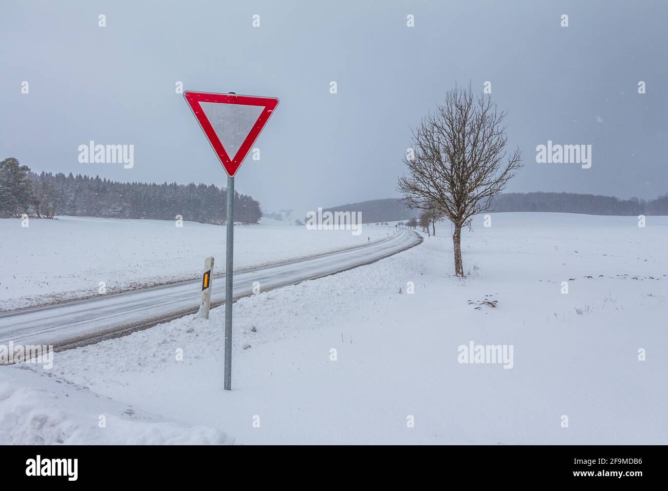 White empty snowy icy winter road track with yield sign. The street ...