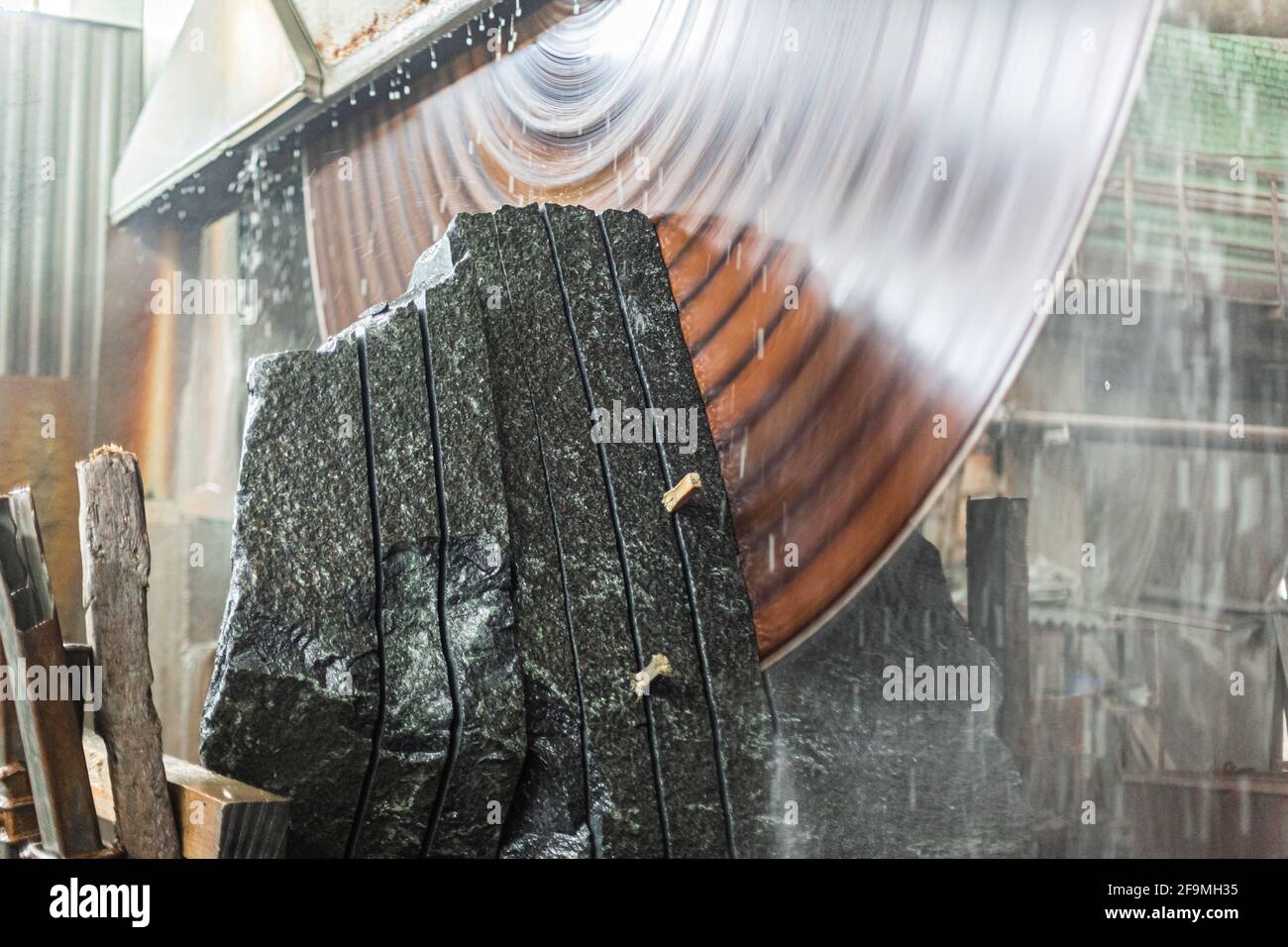 Large industrial cutting machine cuts gray granite stone into slabs ...