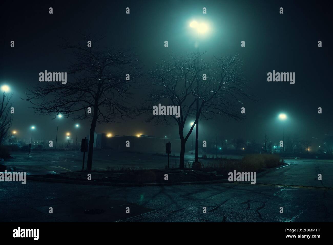 An eerie and foggy city night by a large empty urban shopping mall ...