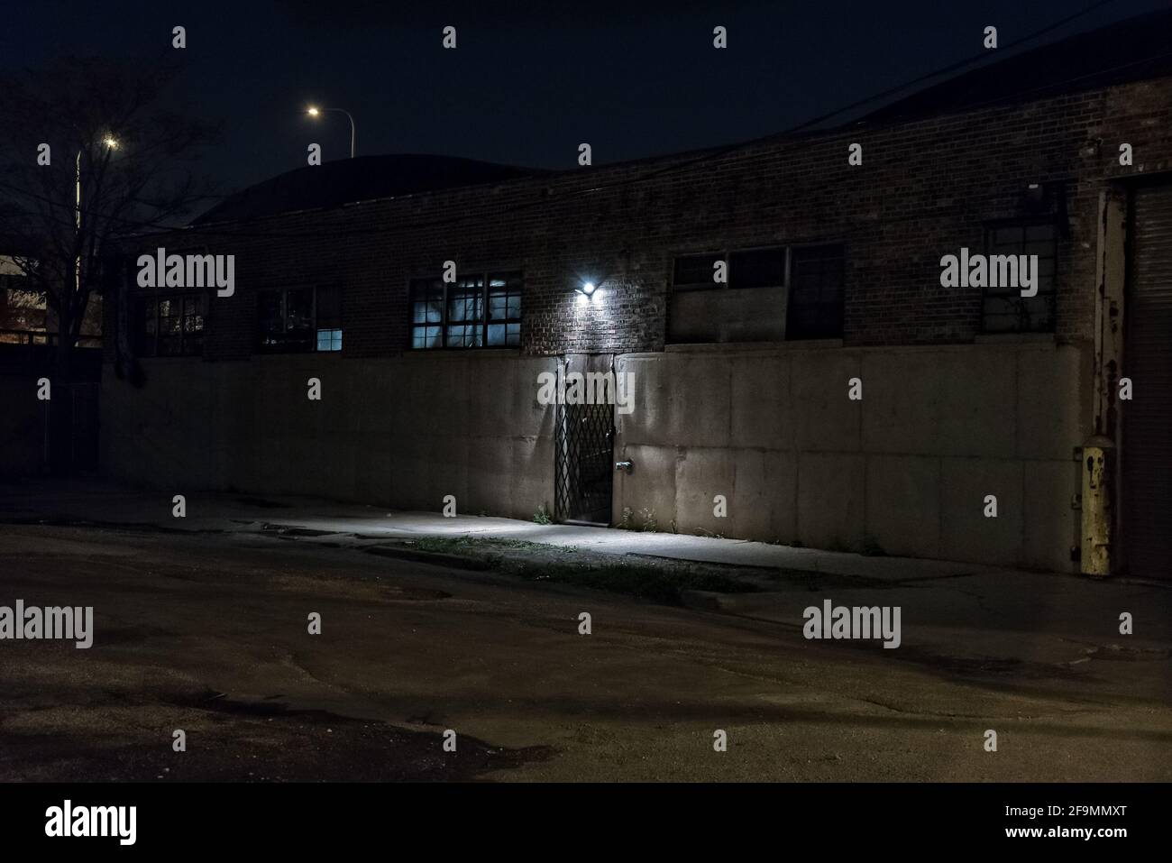 Dark scary alley at night with gated door warehouse entrance Stock ...