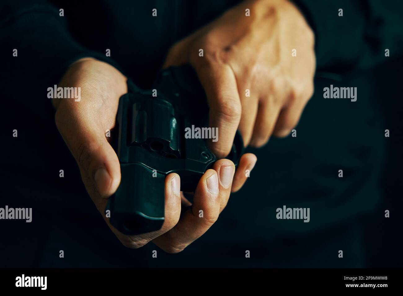 Men's hands check for bullets in revolver barrel. Reloading gun close ...