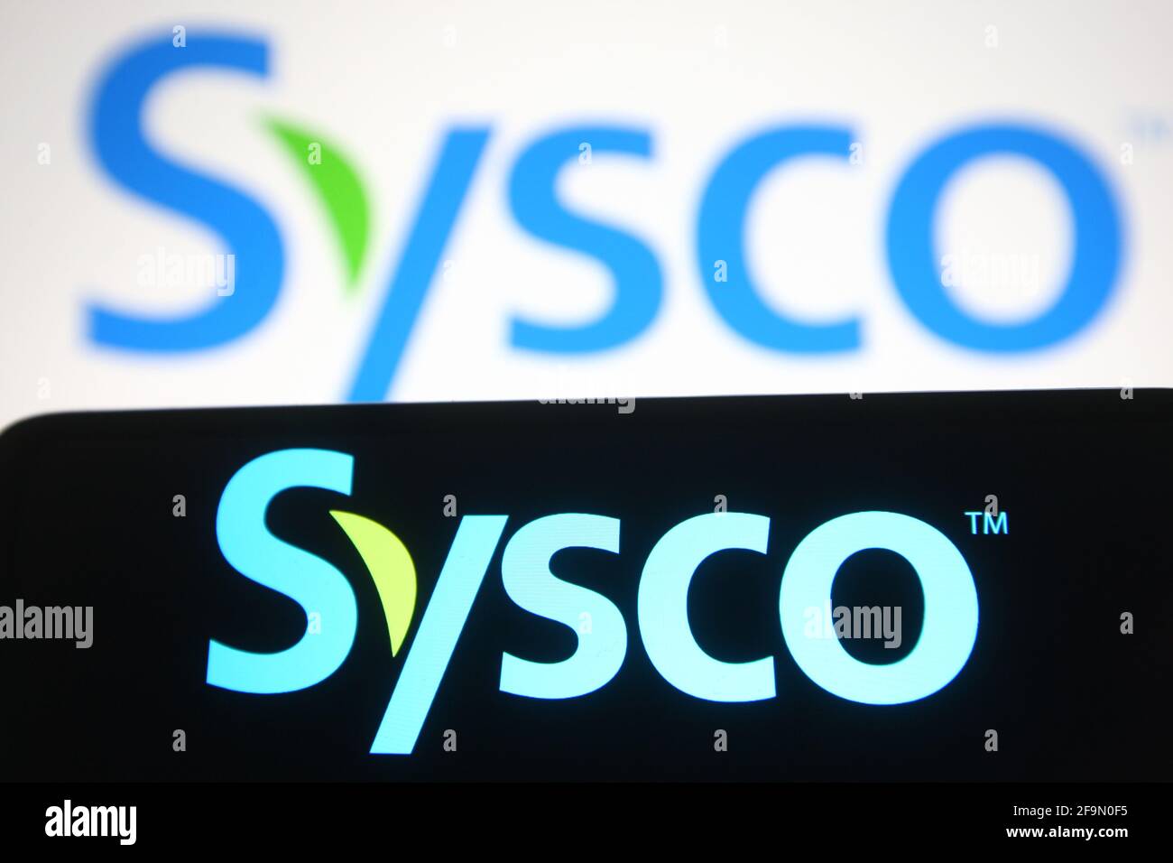 In this photo illustration a Sysco logo is seen on a smartphone and a ...